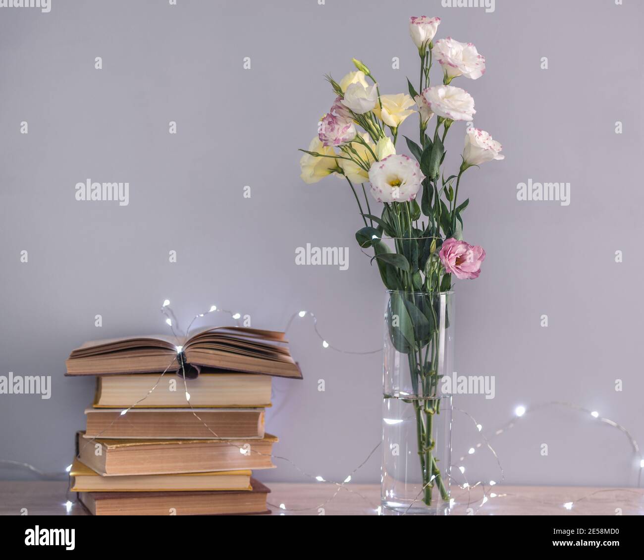 Eustoma flowers bouquet in a vase, stack of old vintage books and ...