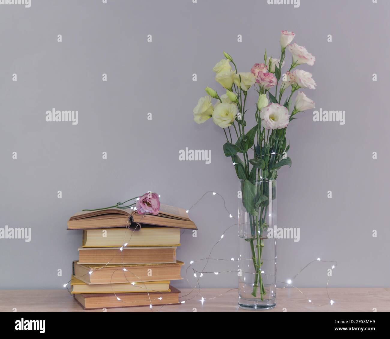 Eustoma flowers bouquet in a vase, stack of old vintage books and ...