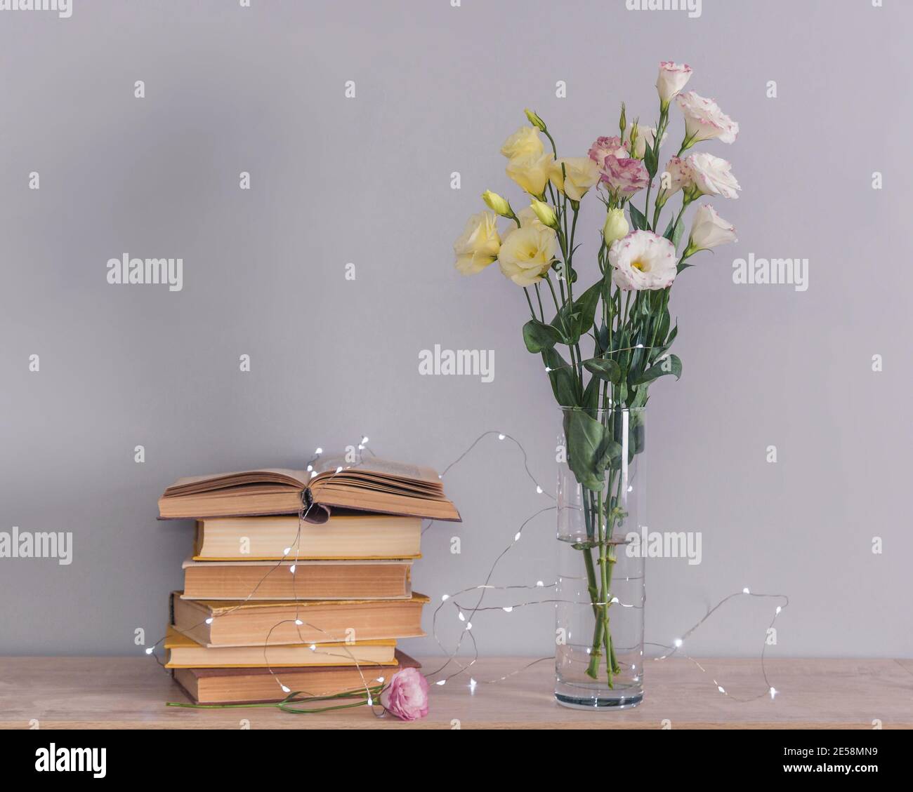 Eustoma flowers bouquet in a vase, stack of old vintage books and ...