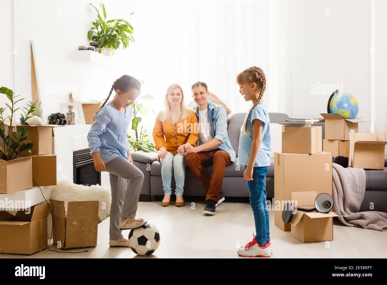 Happy family moving home with boxes around Stock Photo - Alamy