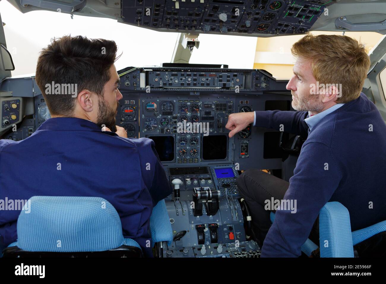 two pilots dressed in uniform flying jet airliner Stock Photo - Alamy
