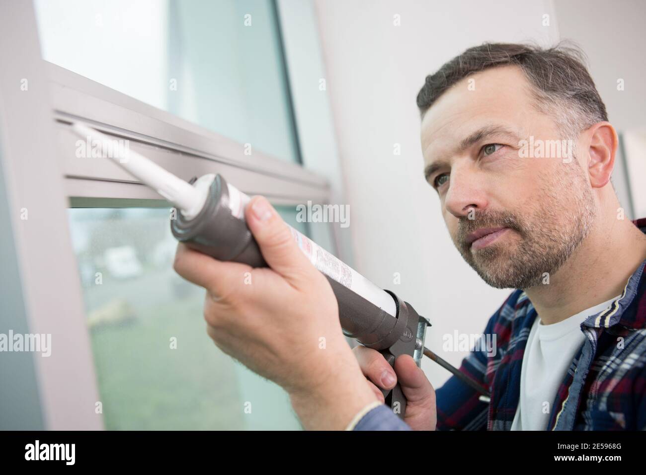 construction worker applying silicone around window frame Stock Photo ...