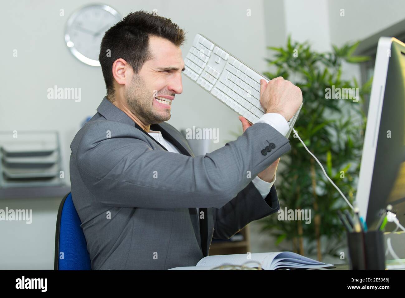 angry businessman poised to strike computer monitor with keyboard Stock ...