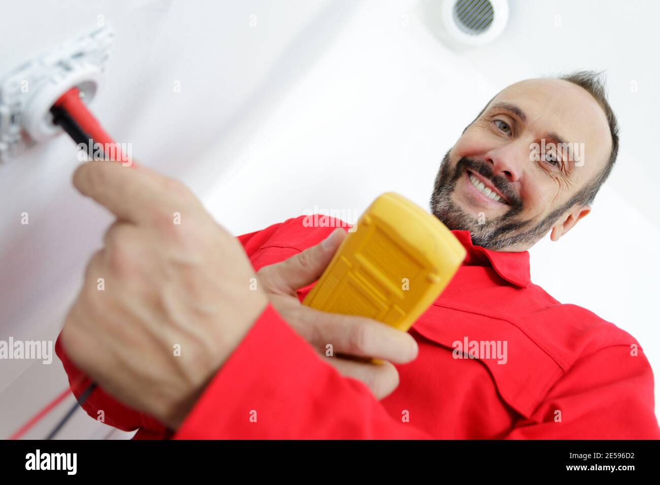 happy electrician checking voltage in electrical wall socket Stock ...