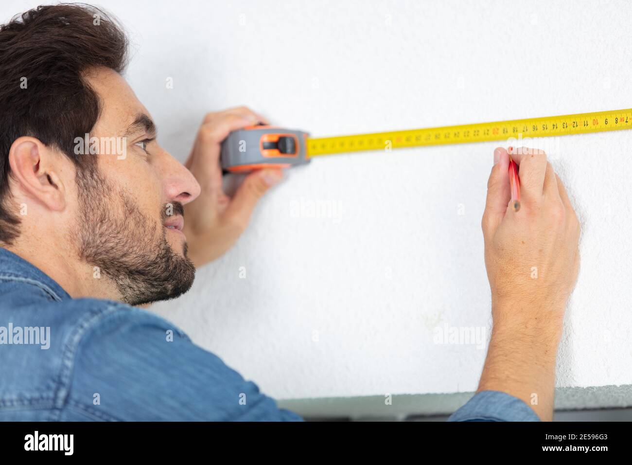 male measuring wall with tape and pencil Stock Photo - Alamy