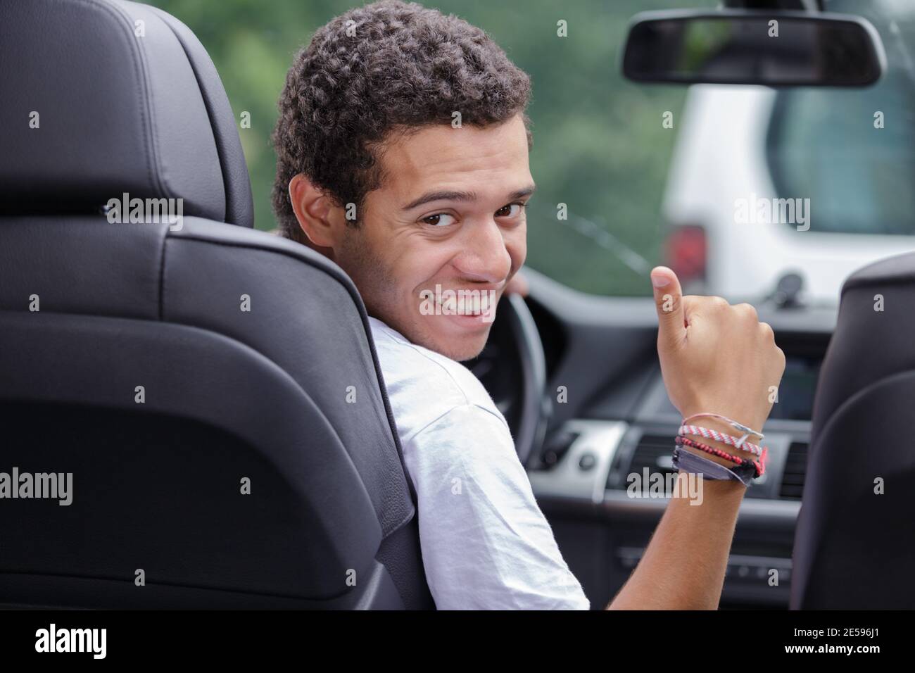 young male driver making thumb-up gesture to back of car Stock Photo ...