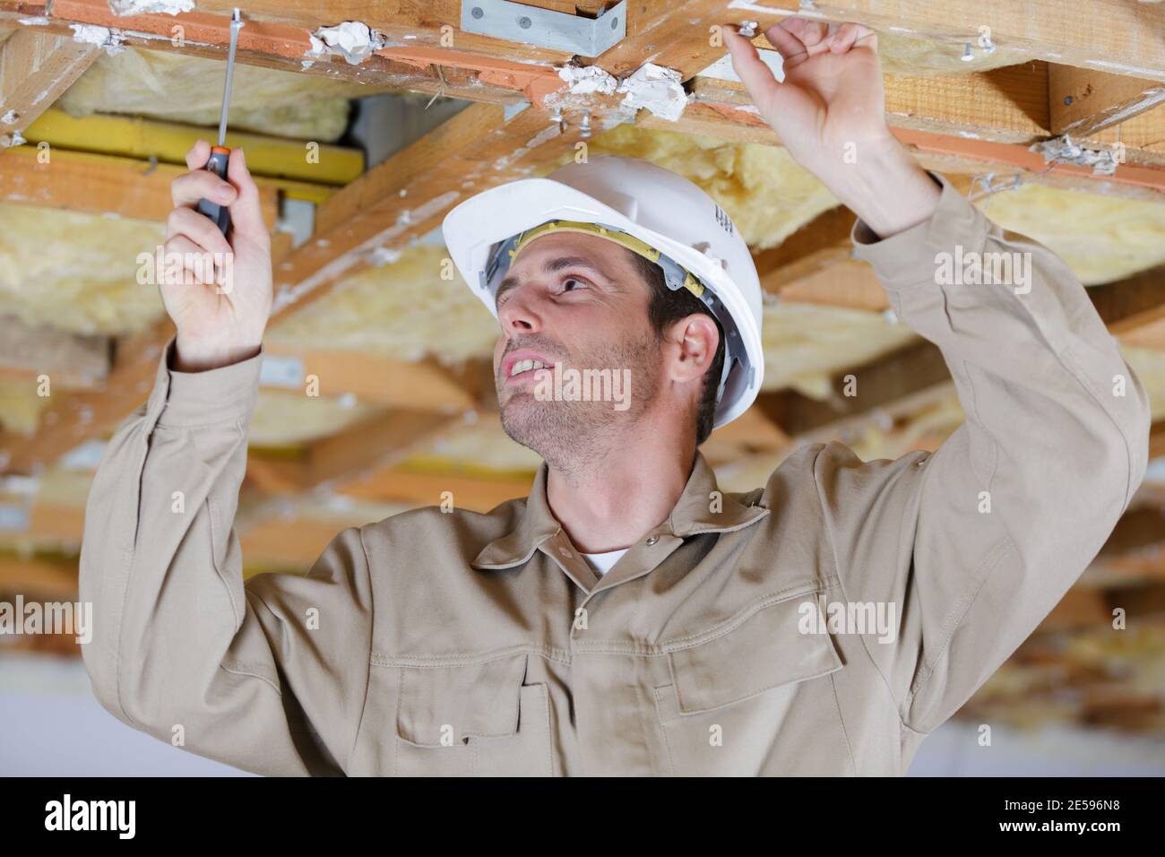 builder screwing fastener into wooden roof joist Stock Photo - Alamy