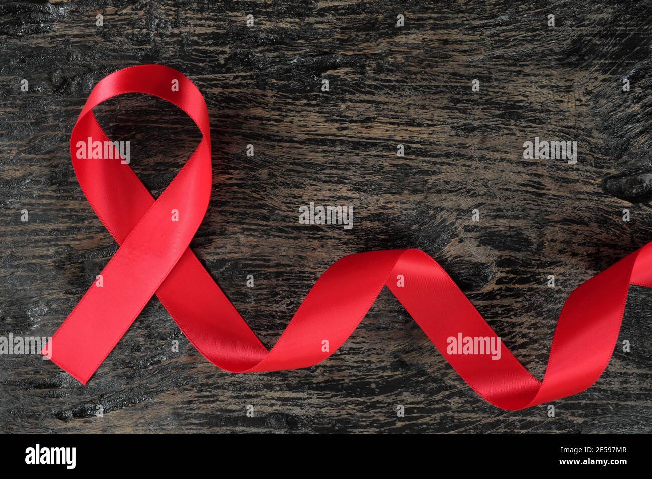 Top view of red ribbon on aged dark wood background. AIDS, HIV, heart ...