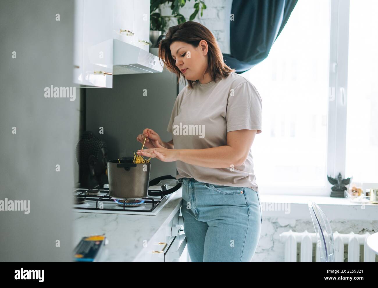 Beautiful brunette young woman plus size body positive cooking in ...