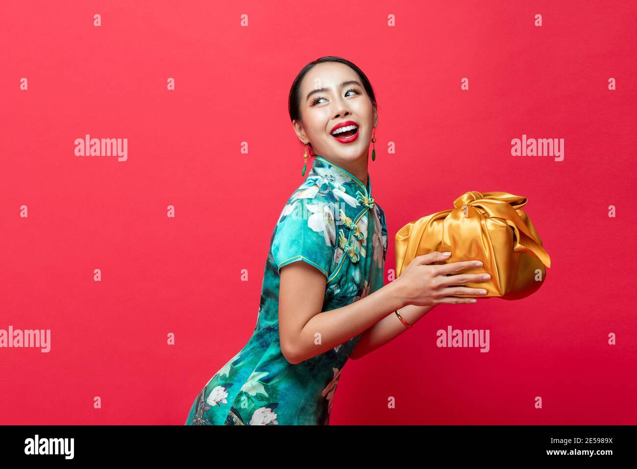 Smiling pretty Asian woman wearing traditional dress holding golden ...