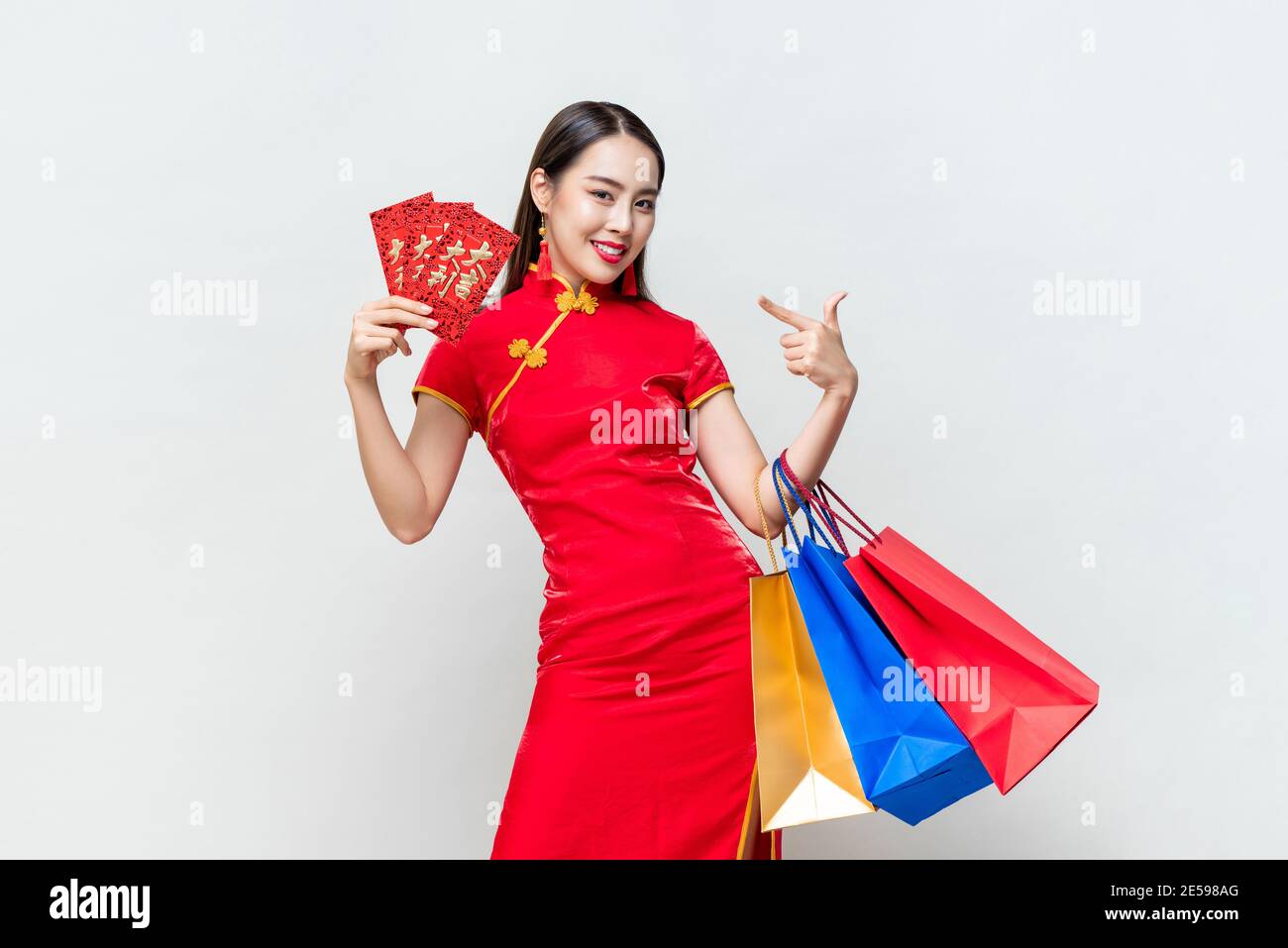 Asian woman in traditional dress holding bags and poiting hand to red ...