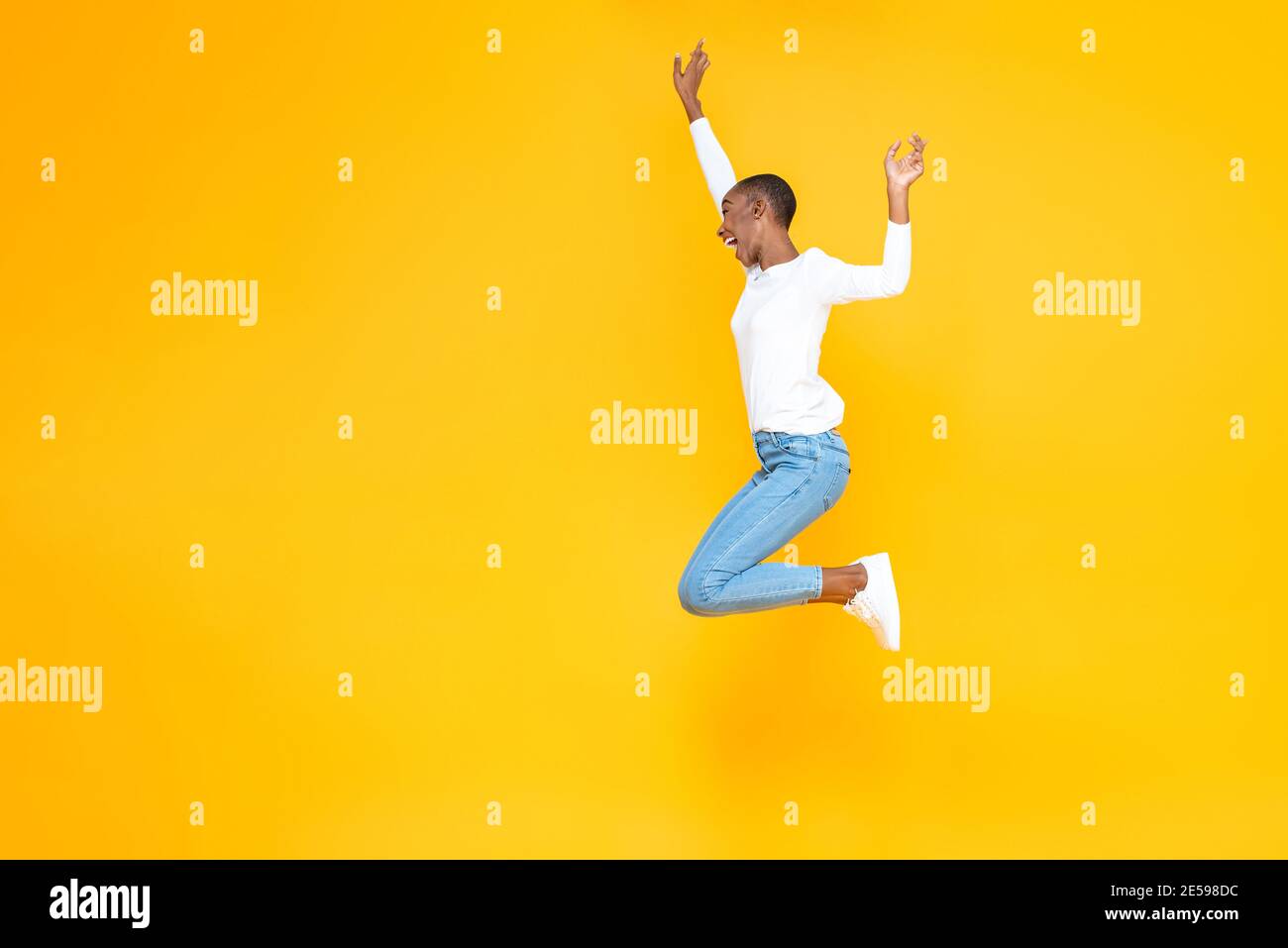 Happy excited African American woman jumping with hands raising in ...