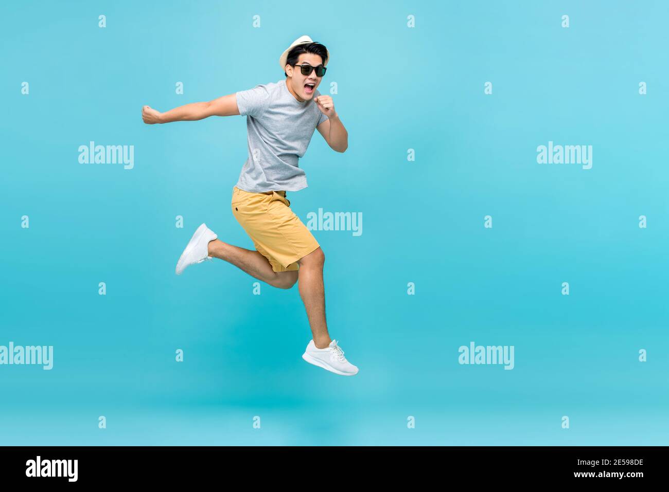 Energetic happy young Asian man jumping studio shot isolated in light ...
