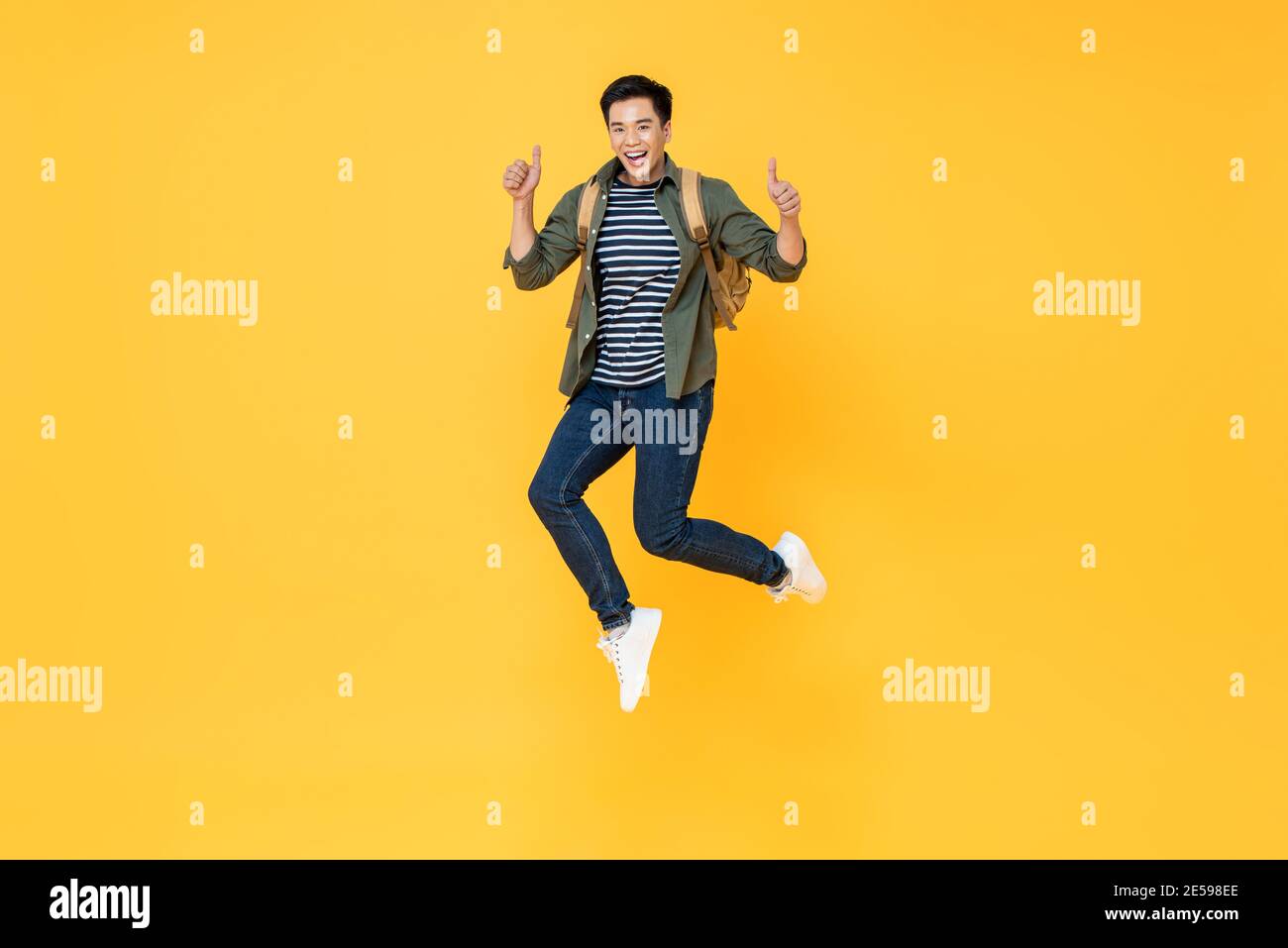 Happy smiling young Asian tourist man with backpack jumping and giving ...