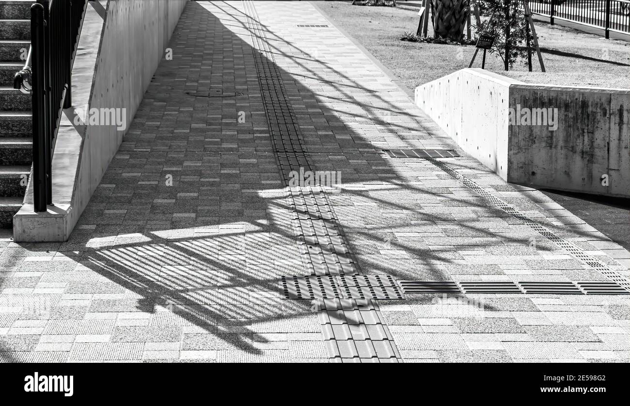 Shadow of the railing of concrete staircase, is cast onto a stone ...