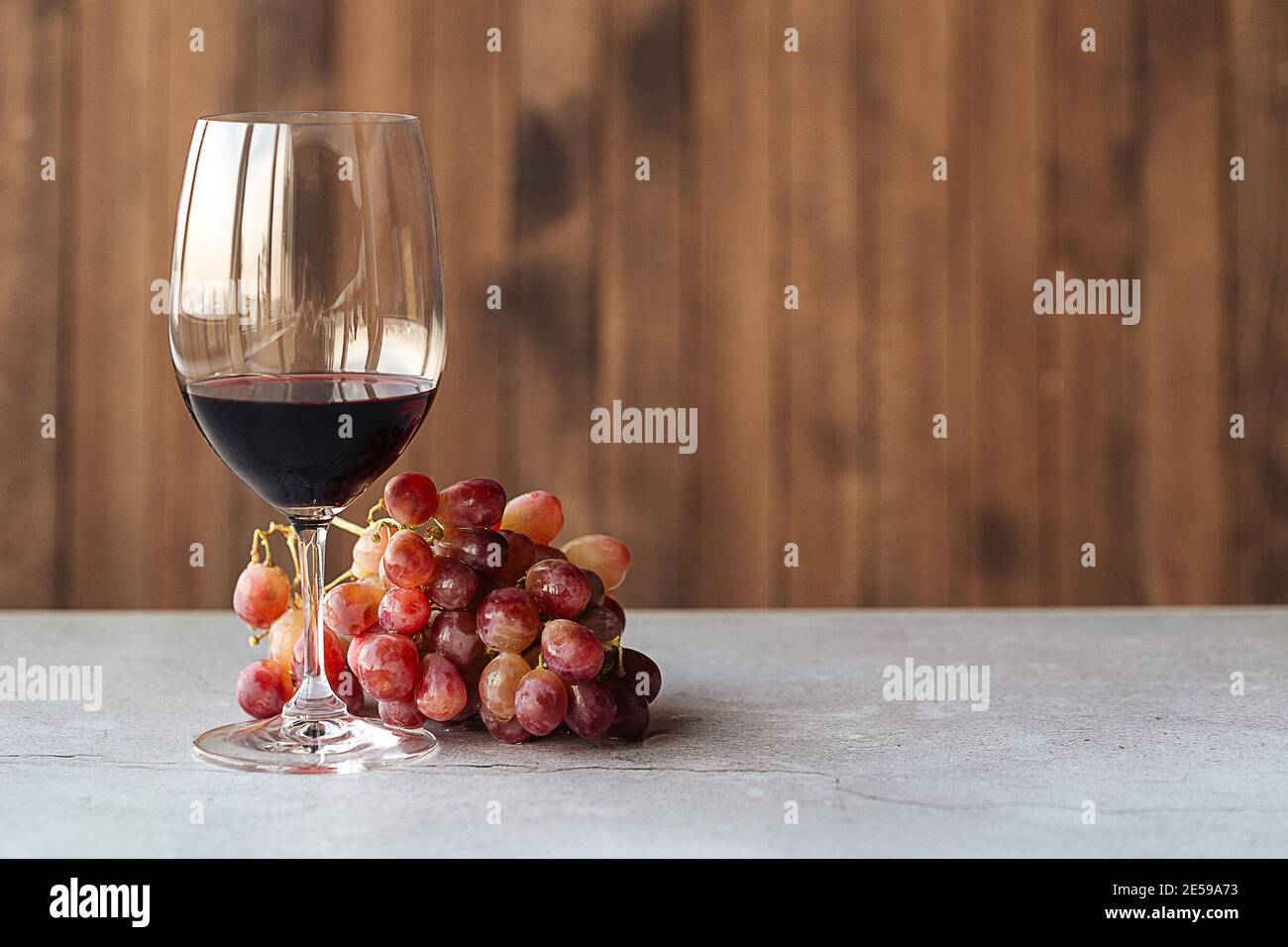 Side view on a glass of red wine with grapes Stock Photo - Alamy