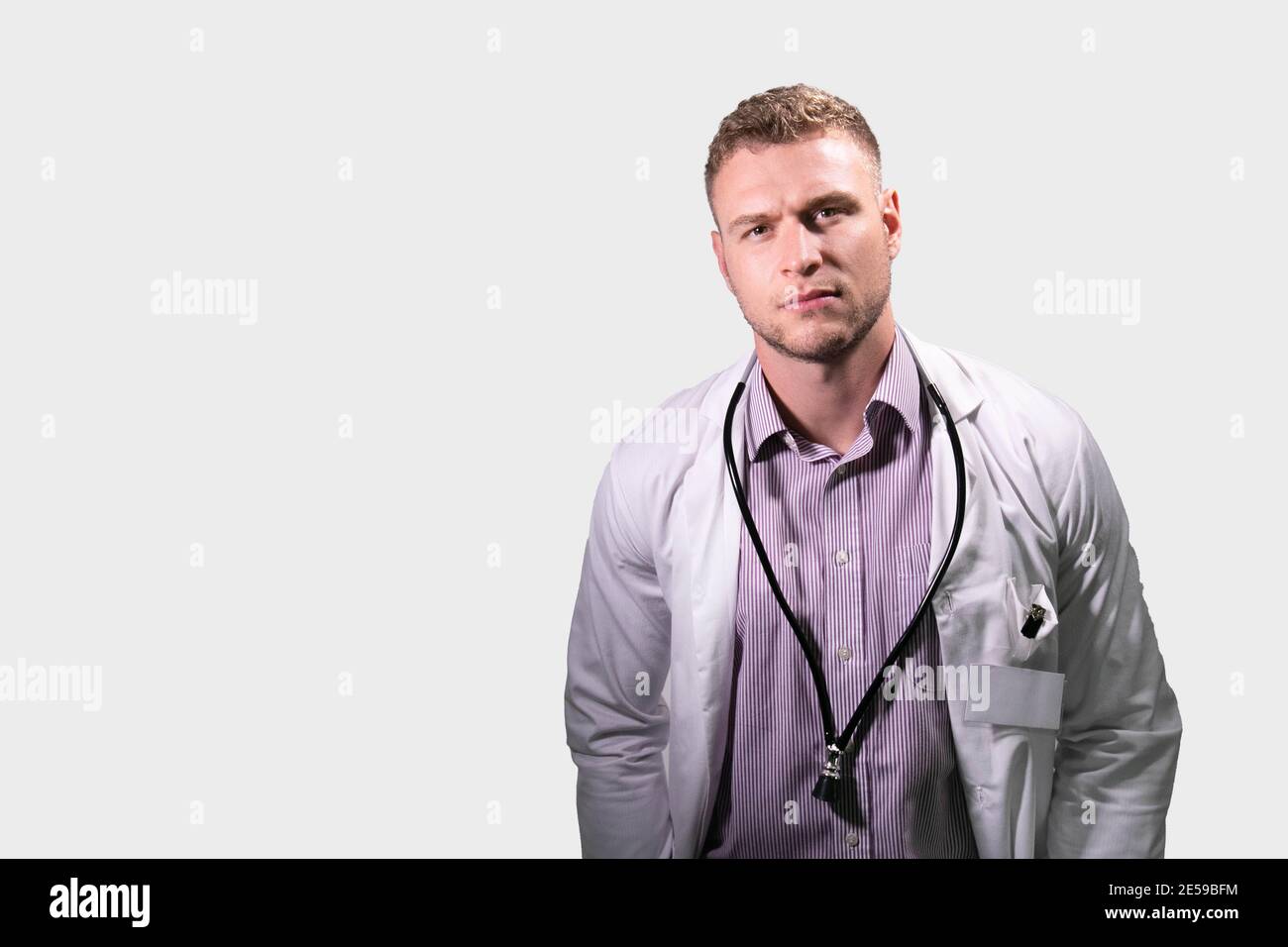 Serious attractive male doctor wearing white lab coat looking at camera ...