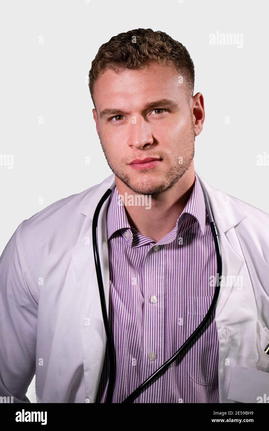 Serious attractive male doctor wearing white lab coat looking at camera ...