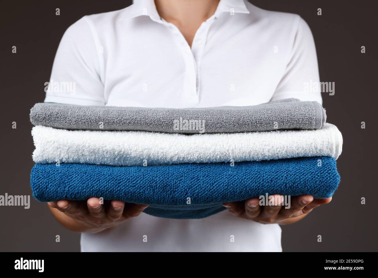 A woman is holding a stack of clean rolled towels Stock Photo - Alamy