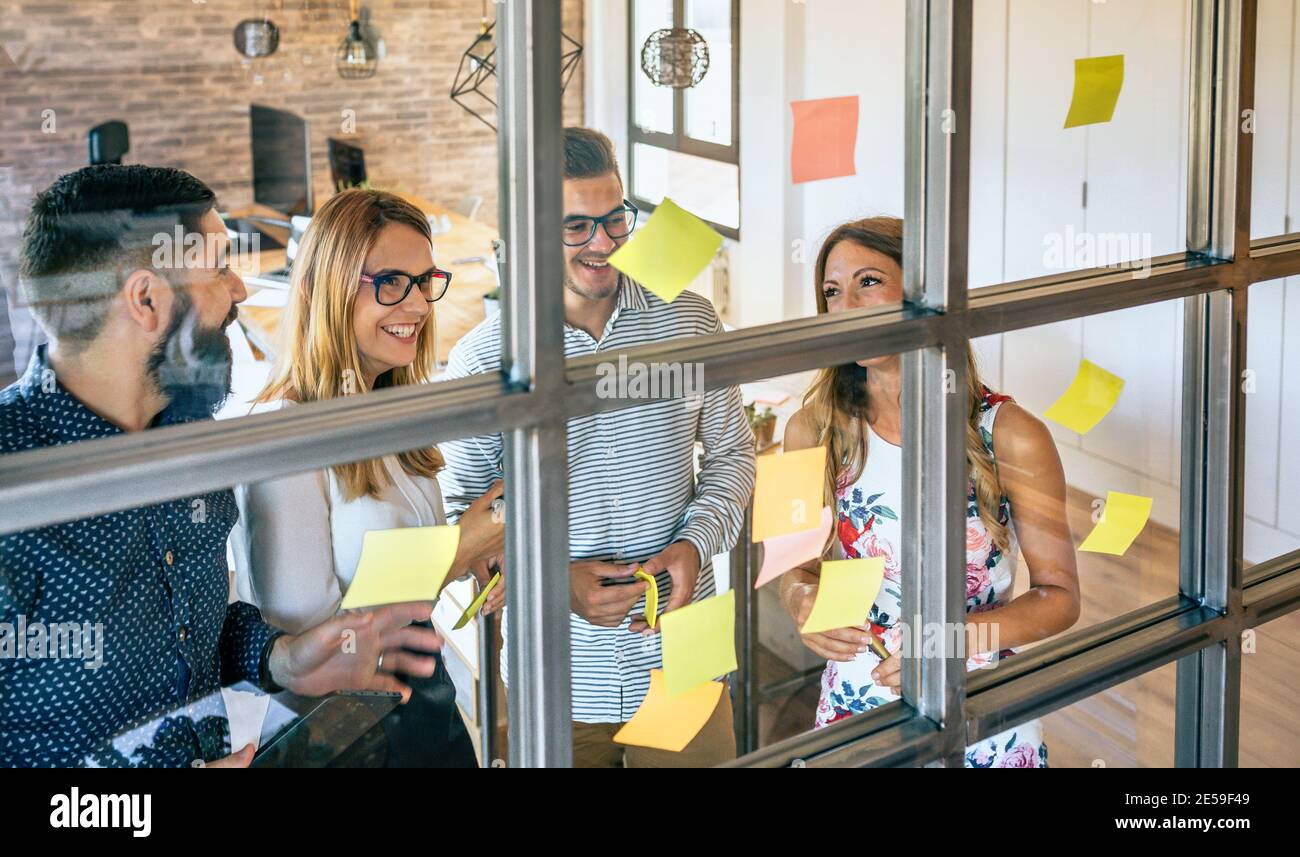 Happy business people in a work meeting placing sticky notes on the ...