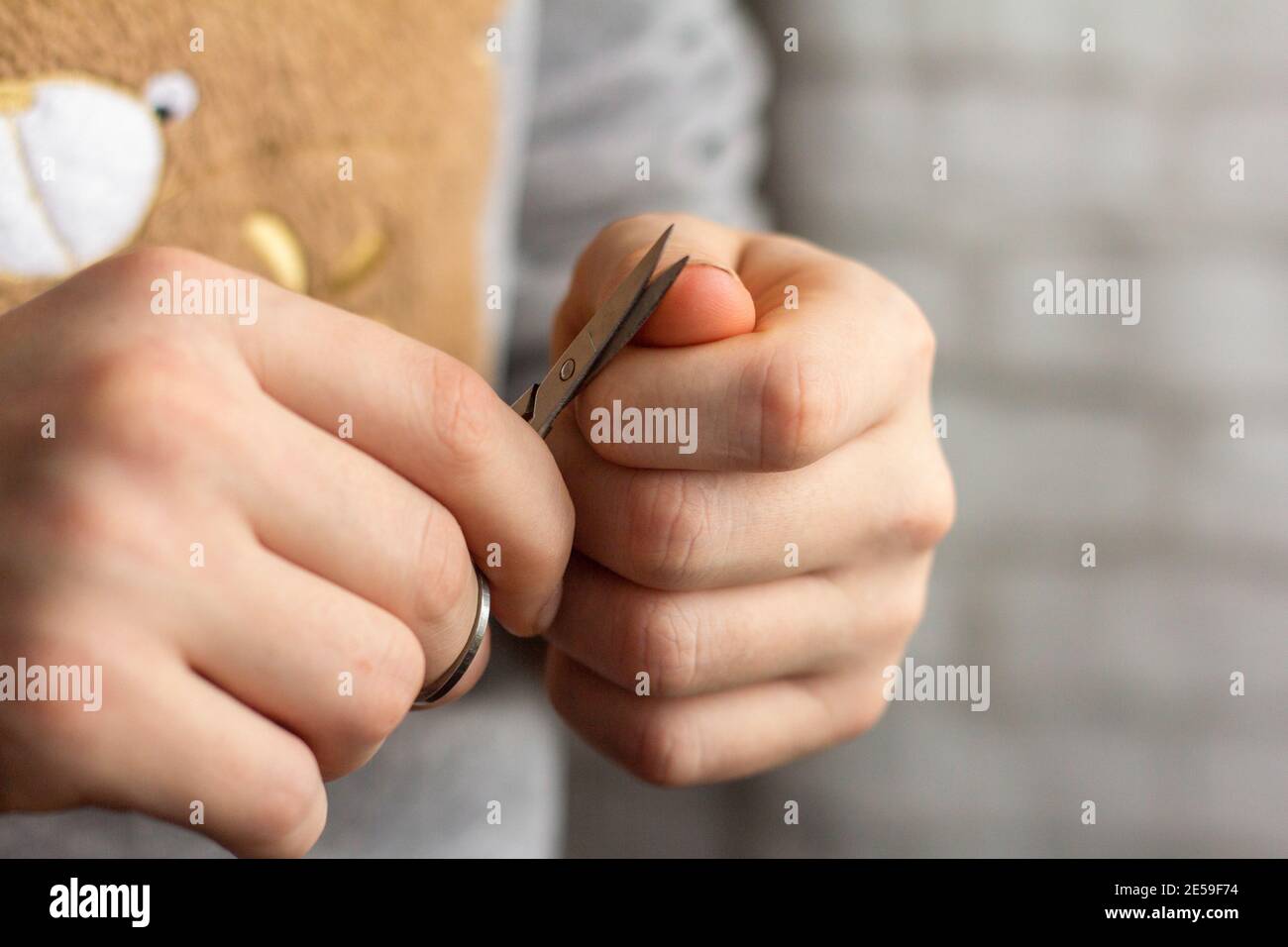 Cut your nails. A young man cuts his nails with nail scissors. Taking ...