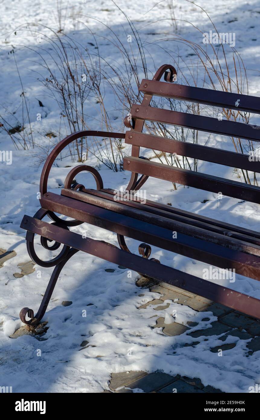 Empty Beautiful brown bench on a winter city street. Wood and wrought ...