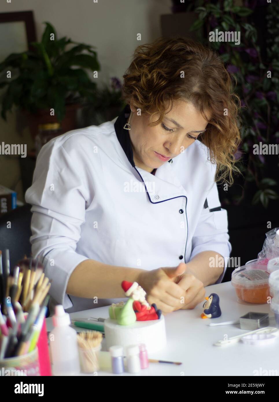 Cake decorating process. Baker uses tools to sculpt fondant patterns ...