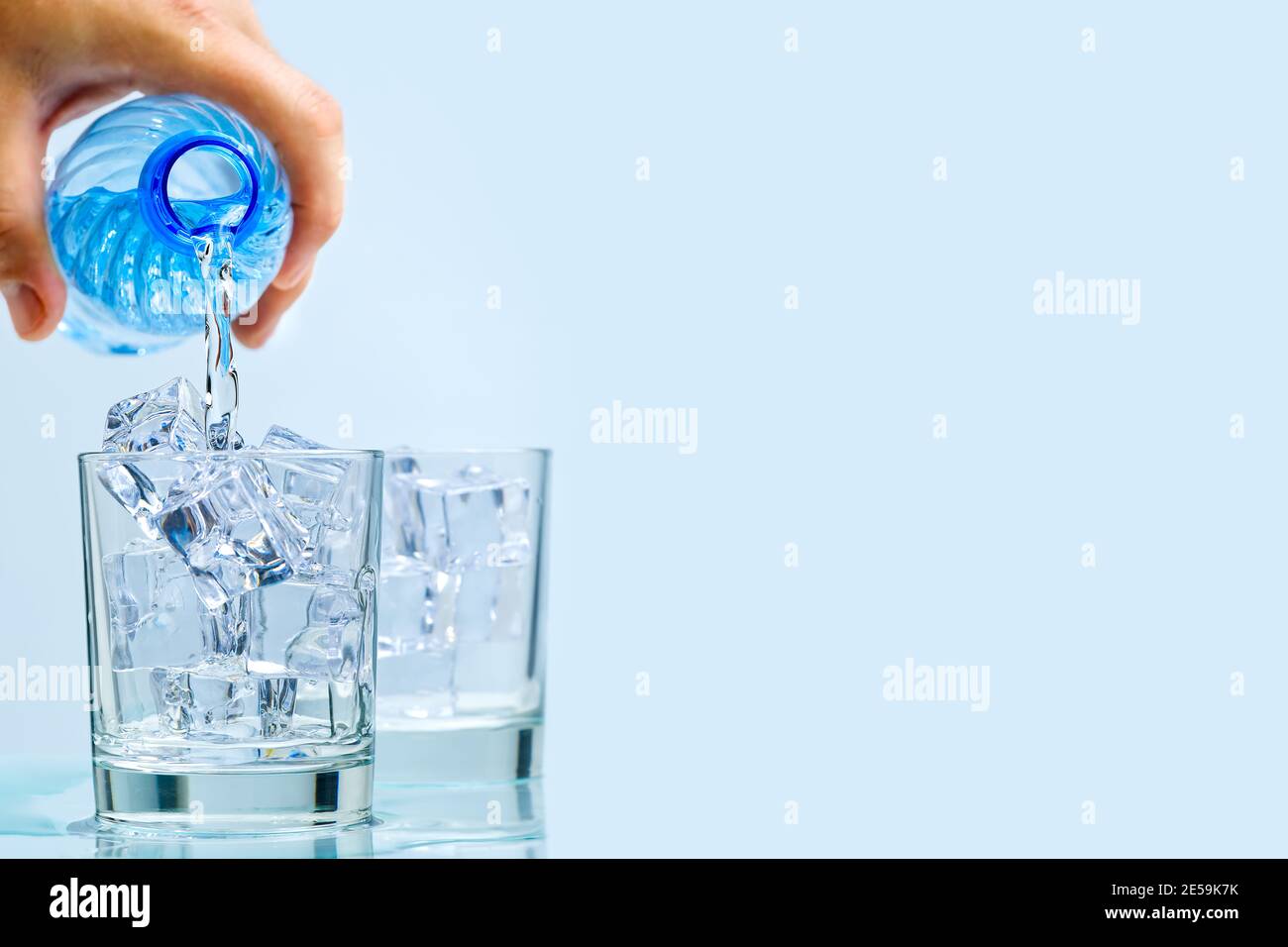 Pouring clean drinking water from blue plastic bottle into glass on ...