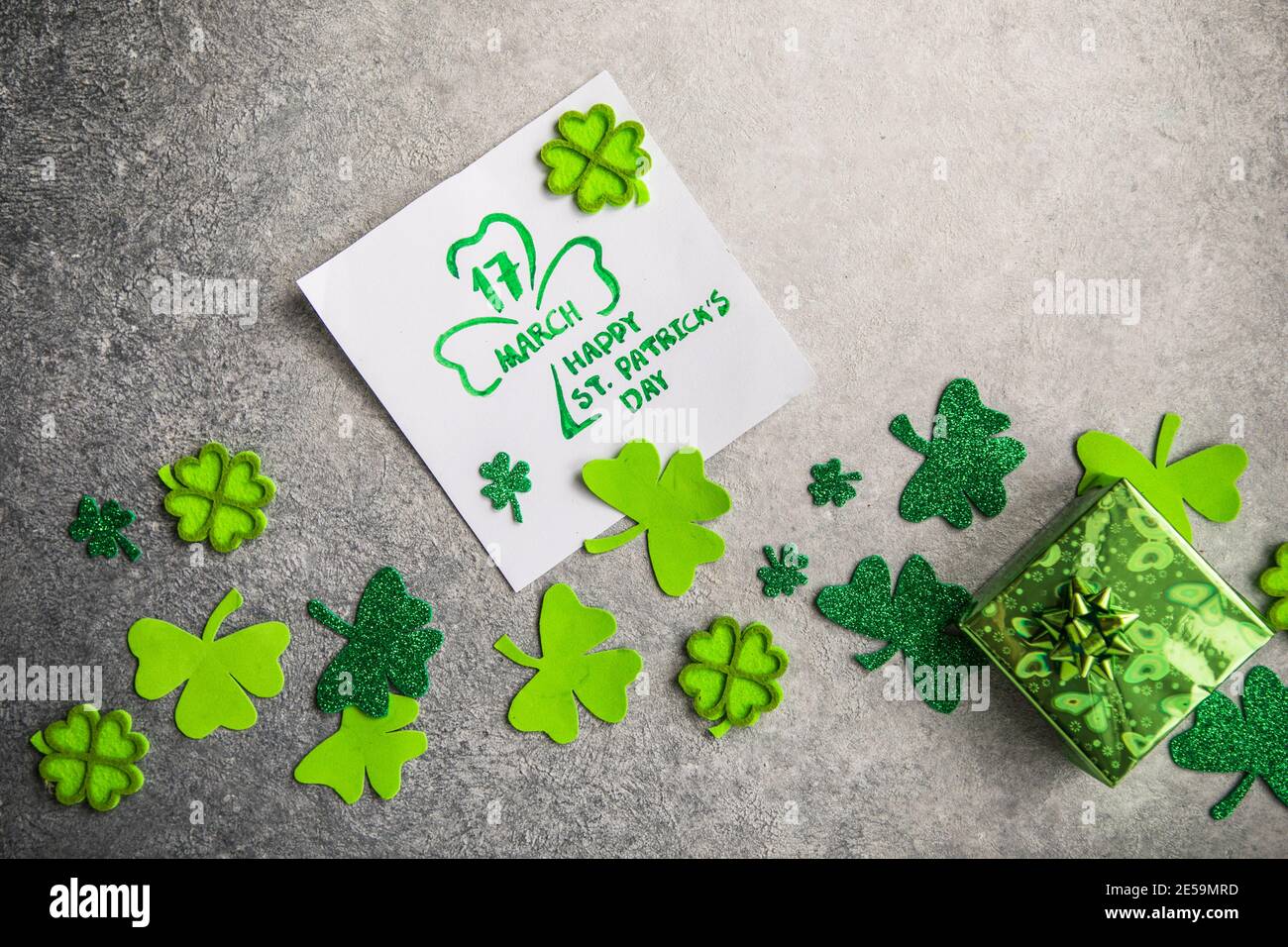 Decorative clover leaves, green gifts box, coins on stone background ...