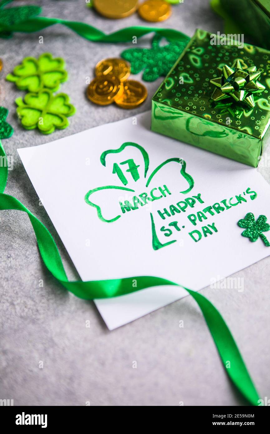 Decorative clover leaves, green gifts box, coins on stone background ...
