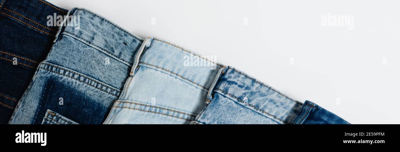 diagonal row of different jeans on white background, top view, banner ...