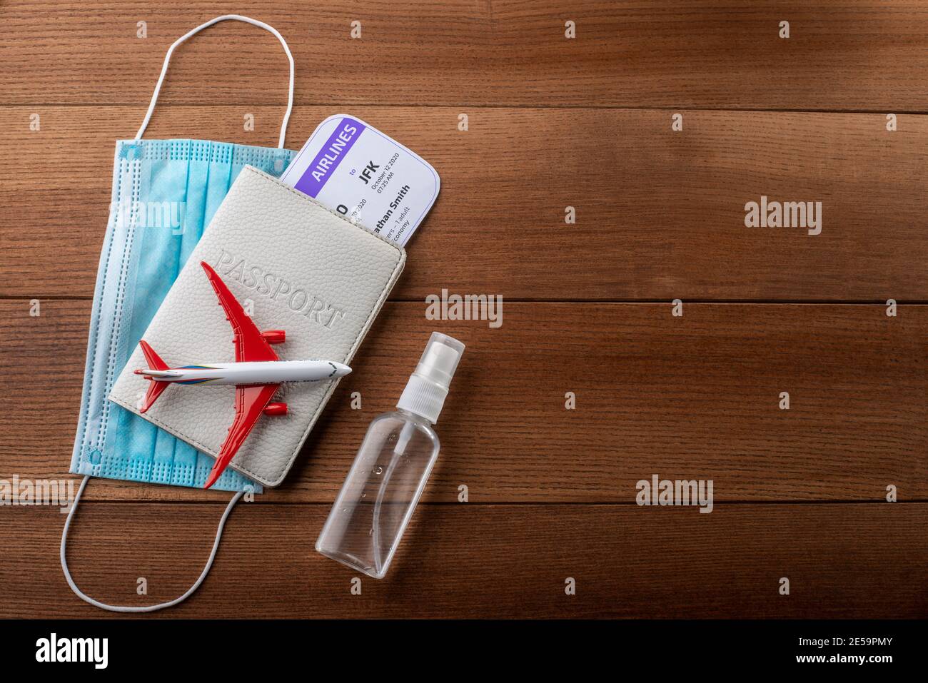 Plane toy, passport with ticket, sanitizer spray and medical face mask ...
