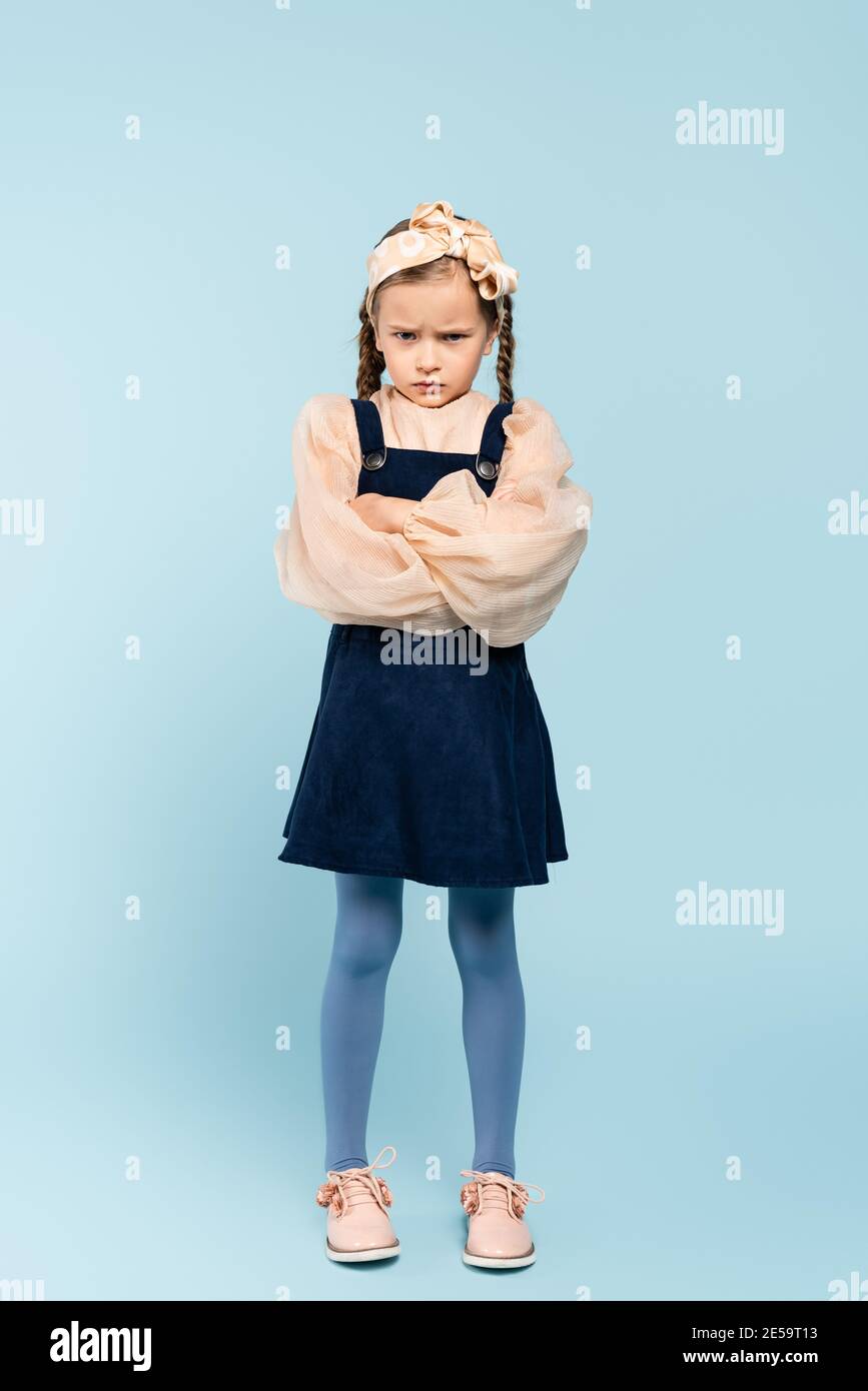full length of offended kid with pigtails standing with crossed arms on ...