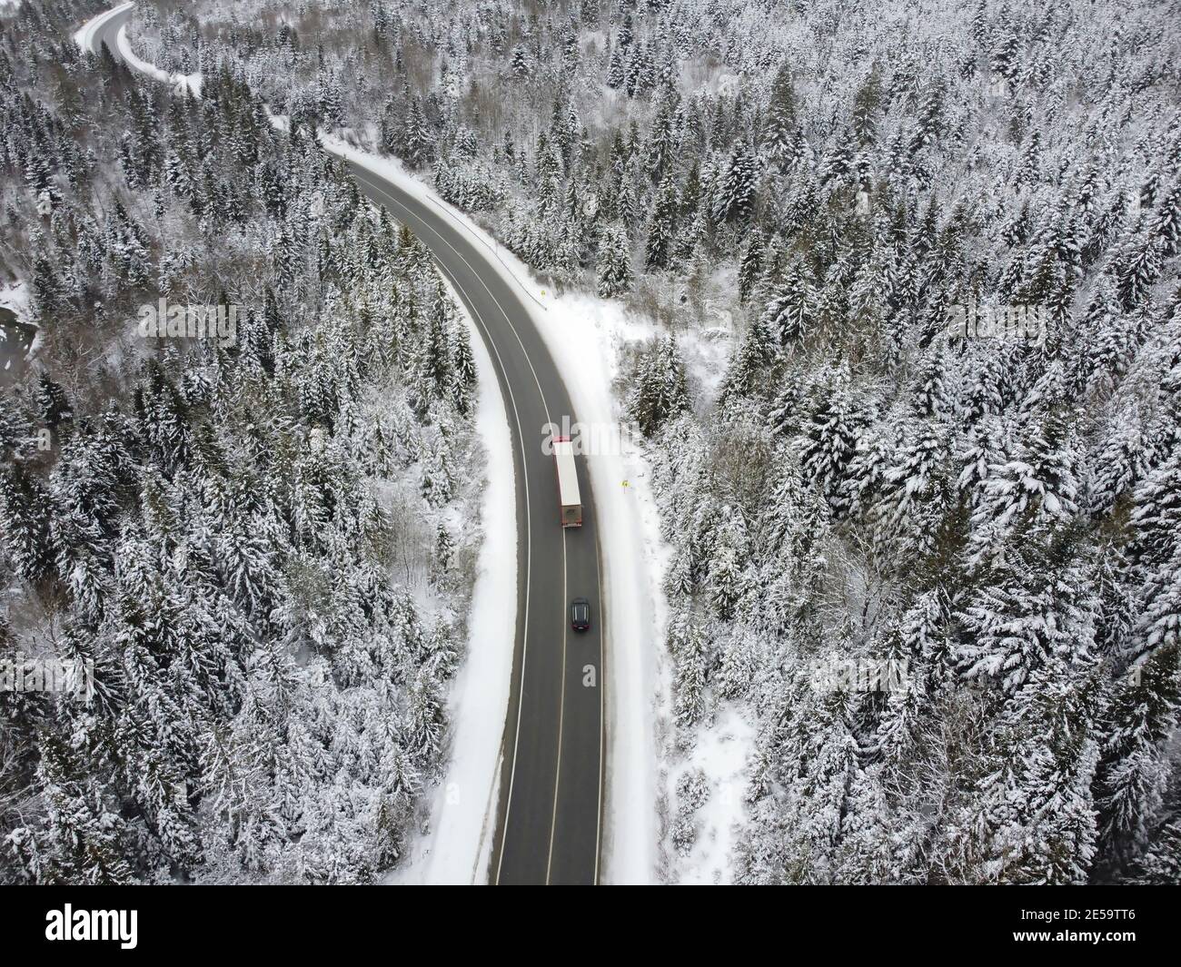Winding road through the woods in winter. asphalt through the pass to ...