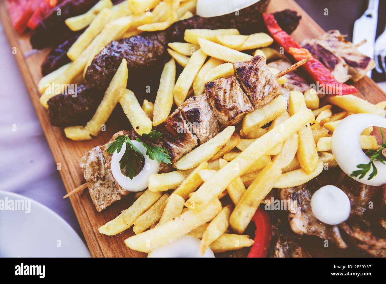 Tasty mixed grilled meat and french fries serving on wooden plate in ...
