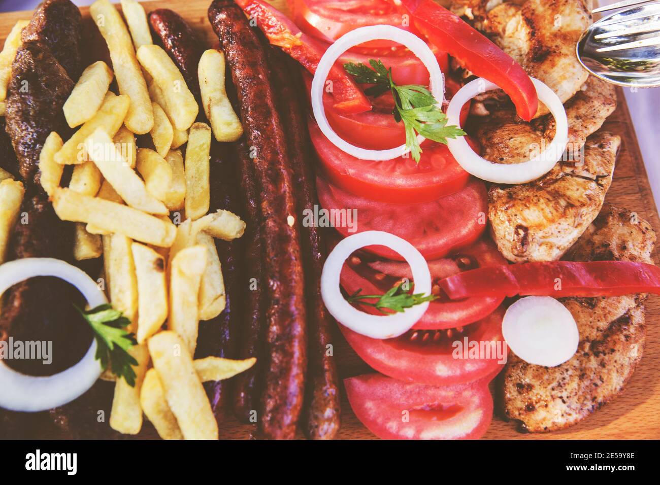 Tasty mixed grilled meat and french fries serving on wooden plate in ...