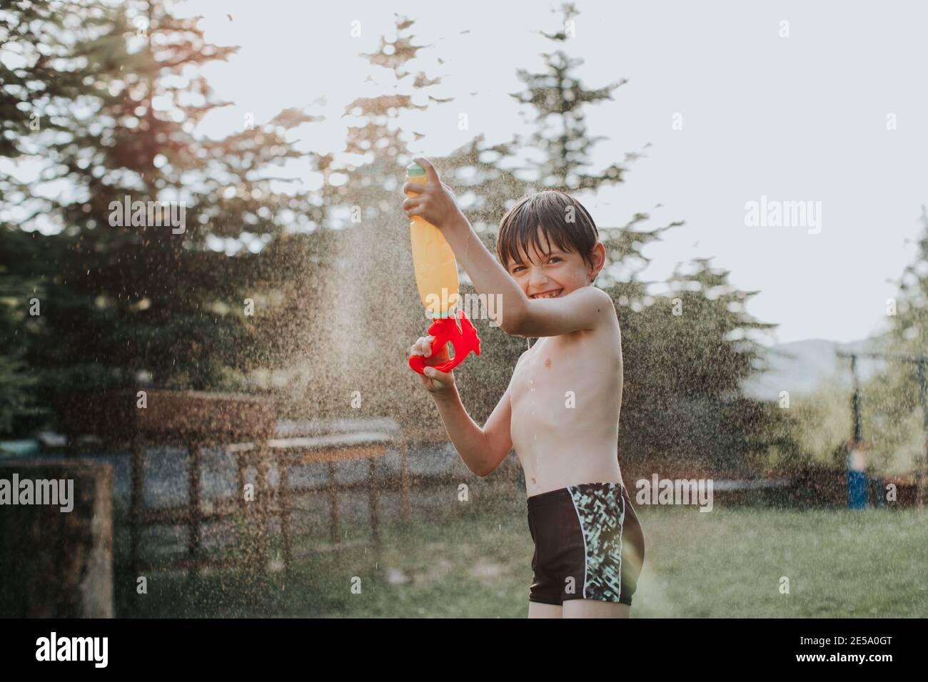 Excited child spraying water all over himself on a hot summer day ...