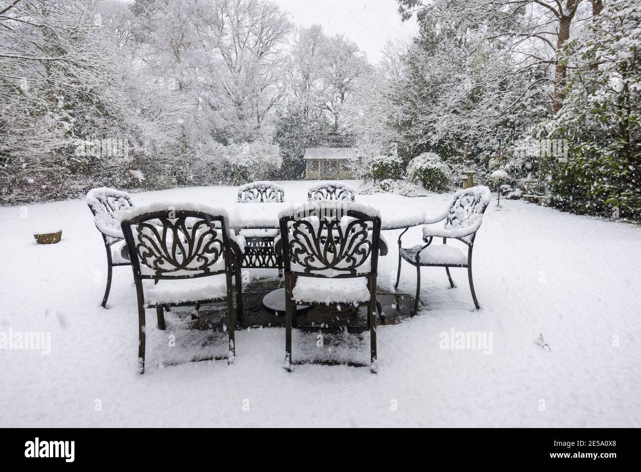 Outdoor tables and chairs on a patio and trees covered in snow during a ...