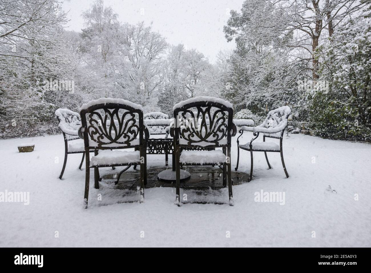 Outdoor tables and chairs on a patio and trees covered in snow during a ...
