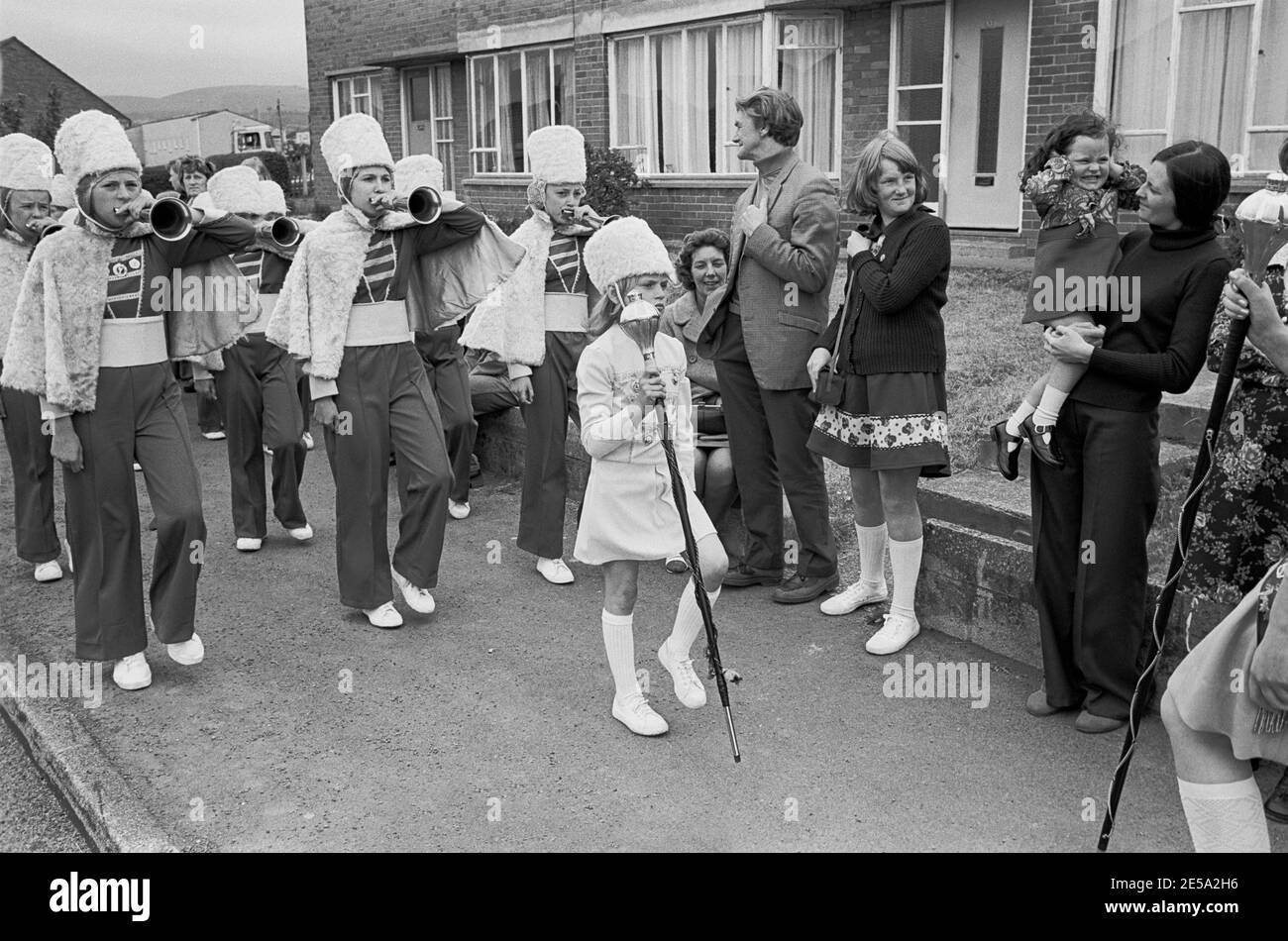 A little girl covers her ears as a noisy jazz band passes during the ...