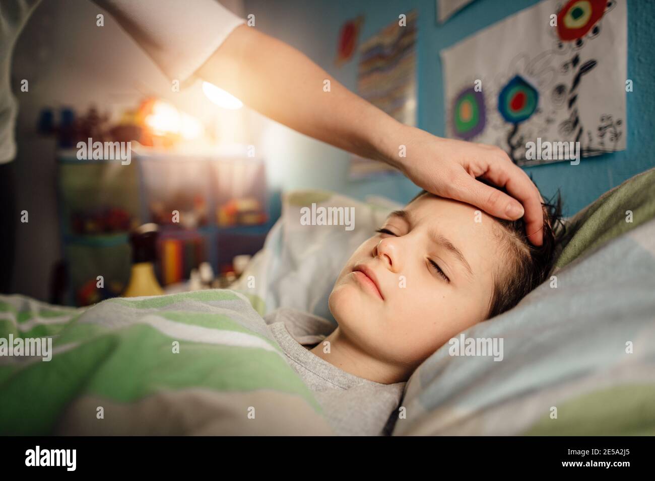 A portrait of a sick child lying in a bed not feeling well. A mother ...