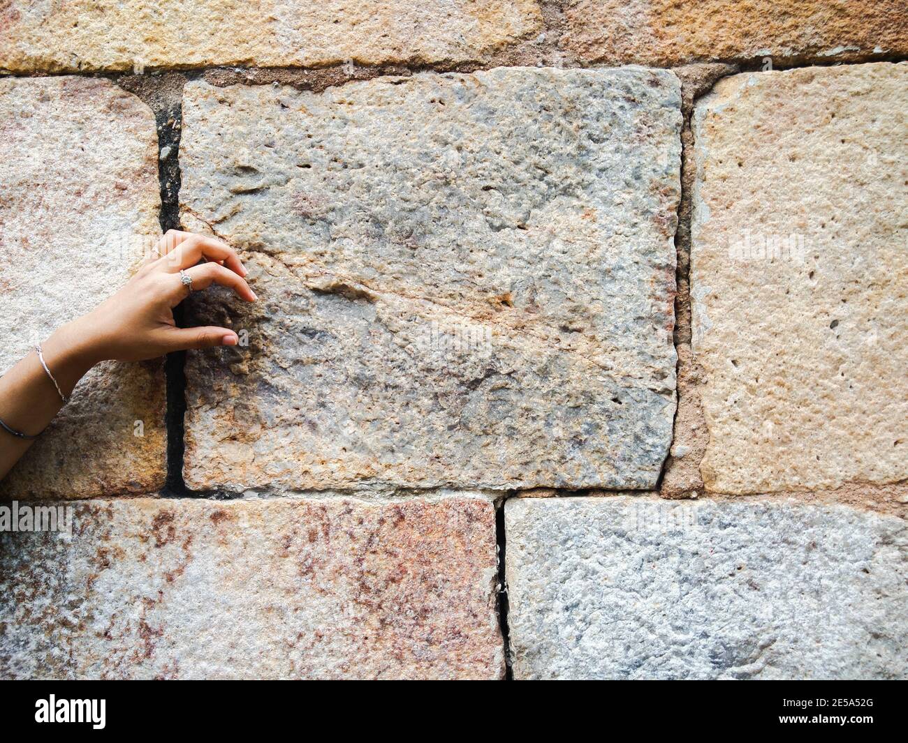 Female hand touching the old stone wall surface and showing the size of ...