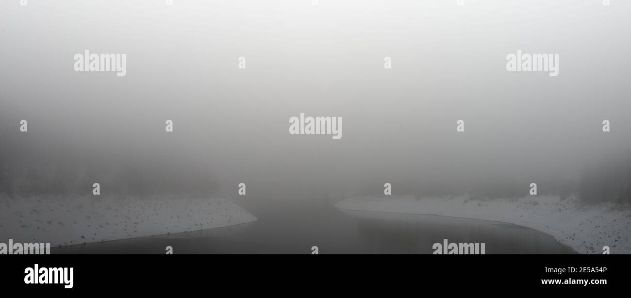 Fog shot of a dam with snowy embankments and dense fog in short ...