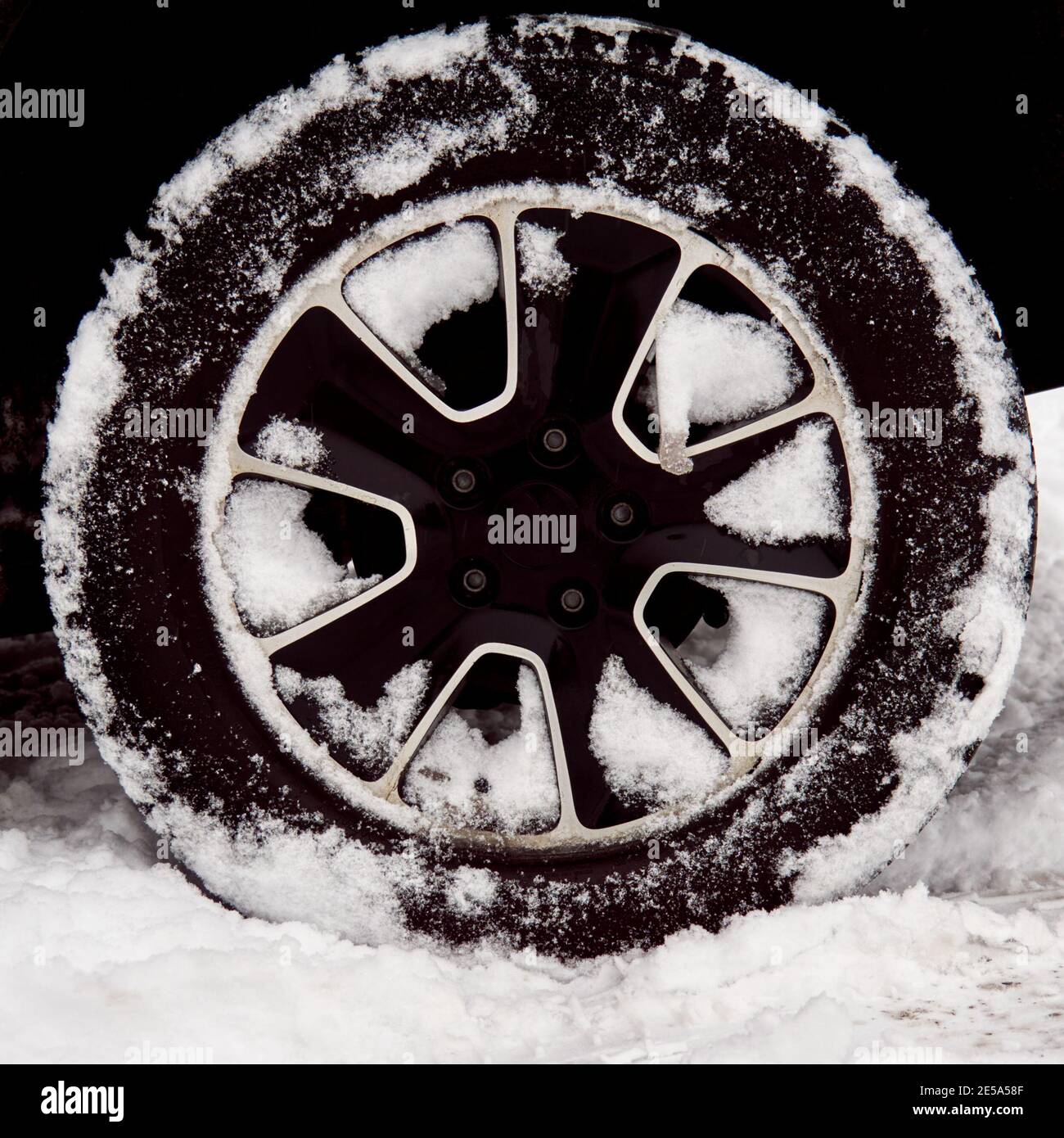 Snow covered rim and tires of car driven through freshly fallen snow ...