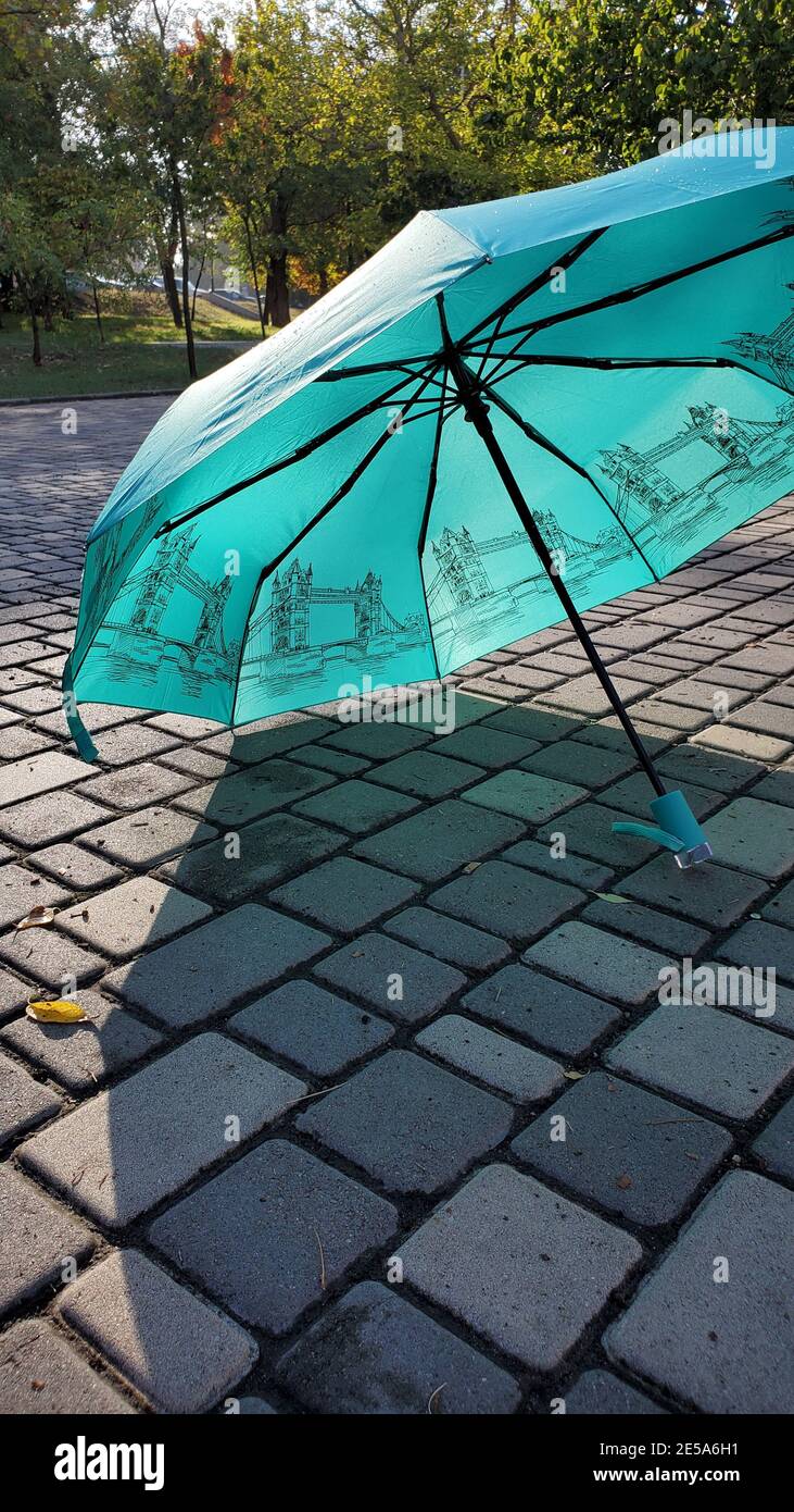 Turquoise color umbrella atop stone tiled pavement wet after rain ...