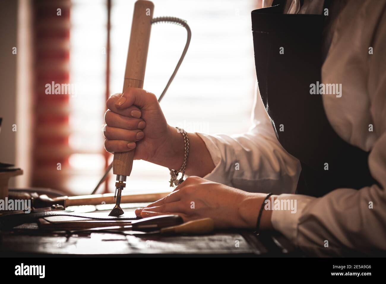 Leather handbag craftsman at work in a vintage workshop. Small business ...