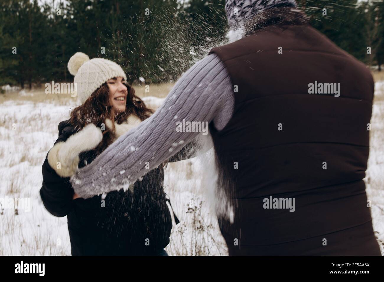 The woman throws a snowball at the man and dodges the snow Stock Photo ...