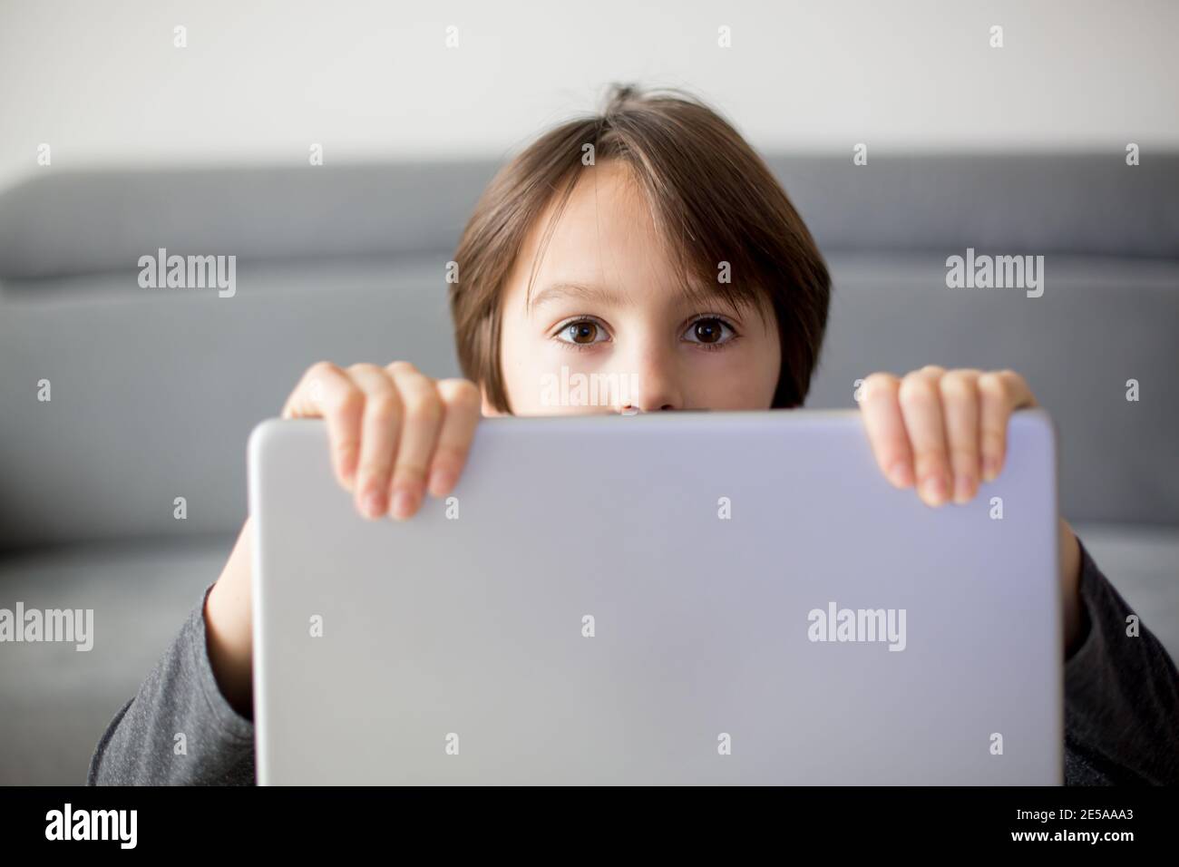 Preteen child, hiding behind notebook, online education, games and fun ...