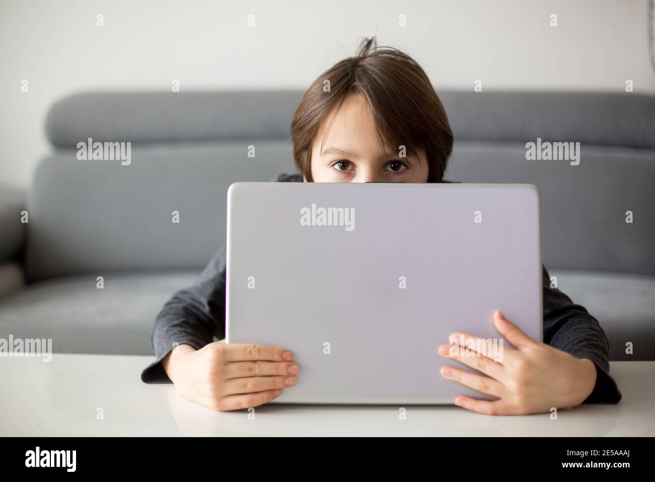 Preteen child, hiding behind notebook, online education, games and fun ...