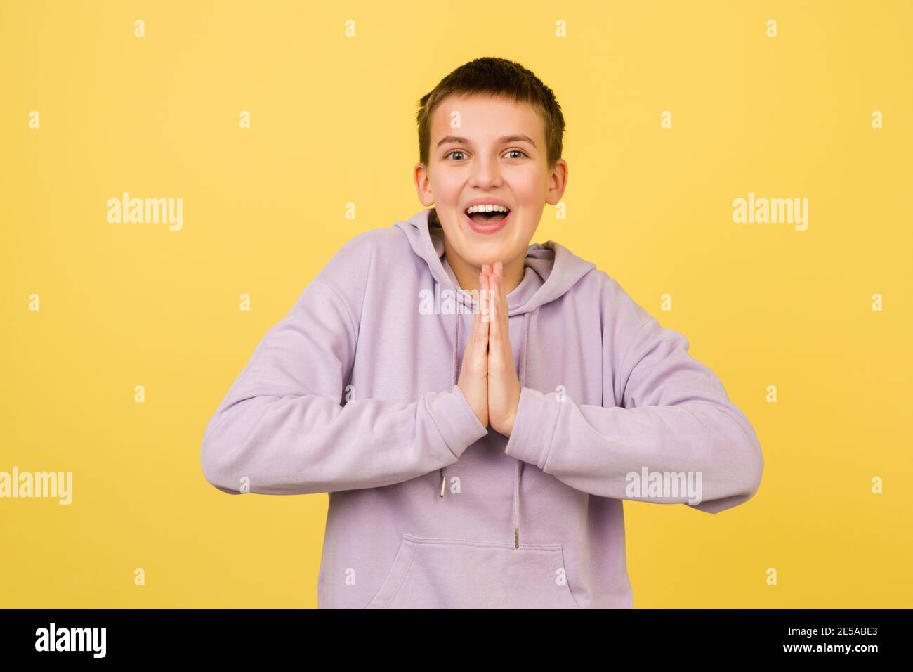 Praying, smiling. Caucasian girl's portrait isolated on yellow ...
